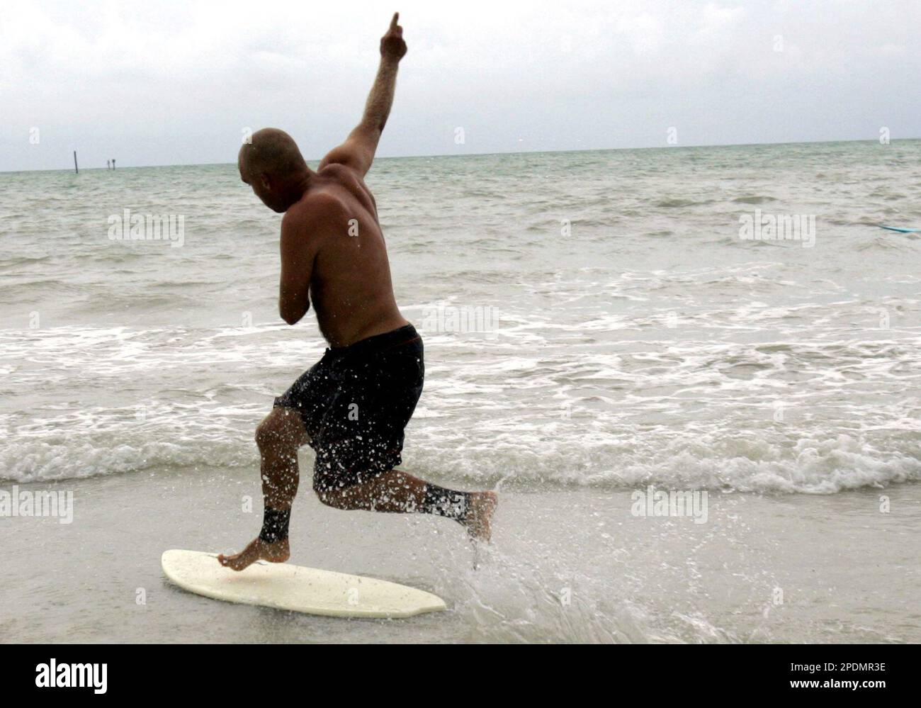 Key West resident Dustin Burgh slides across the sand on a skim board ...