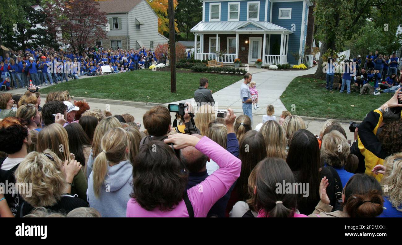 A large crowd watches Jeff Novak, center, carry his 2-year-old daughter ...