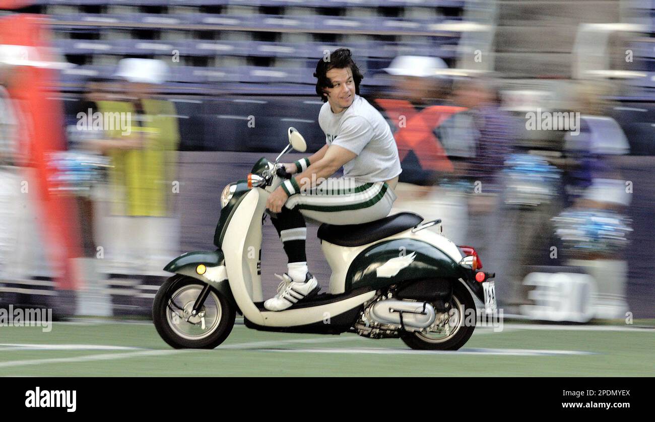 Actor Mark Wahlberg rides a moped on the football field at Texas ...