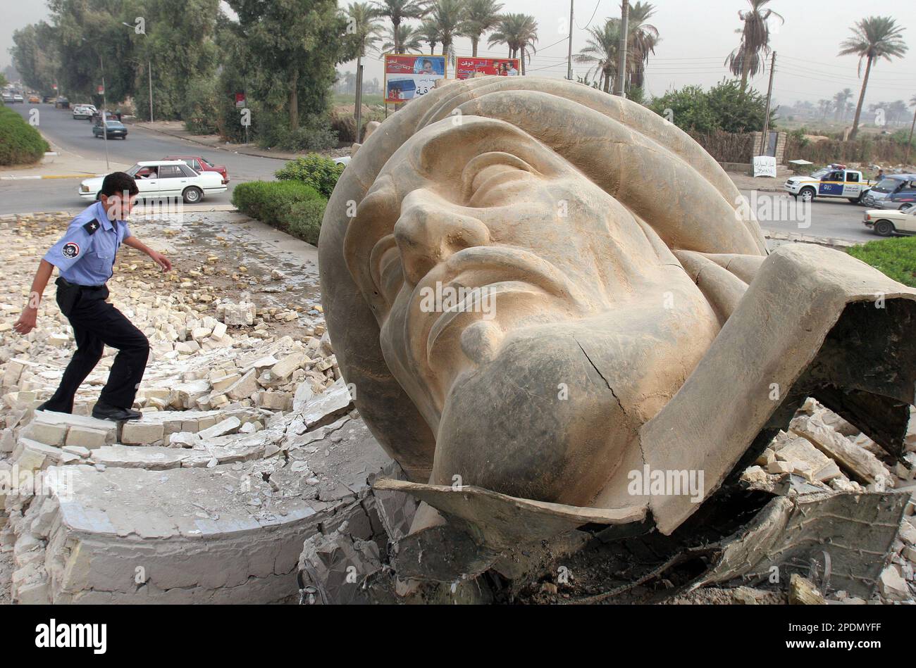 An Iraqi policeman approaches the toppled statue of caliph Abu Jaafar ...