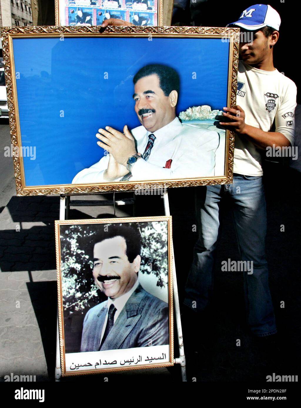 A Jordanian worker displays pictures of the former Iraqi leader Saddam ...