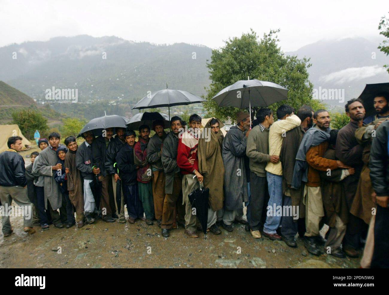 Earthquake victims stand in line during a relief distribution near Uri ...