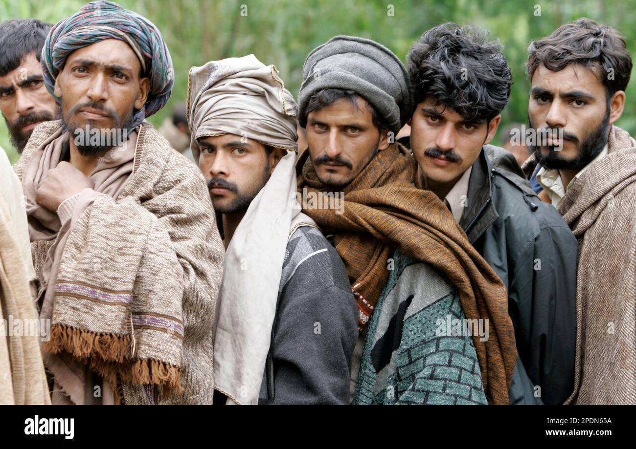 Kashmiri men wait in line to receive food and blankets as relief aid at ...