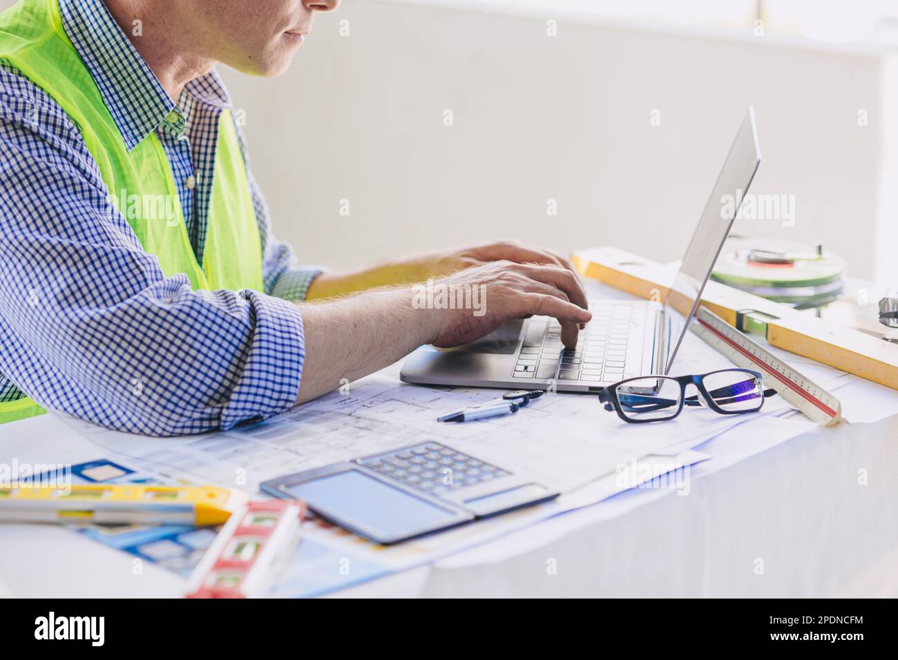 Construction engineer builder working at desk typing on laptop computer ...