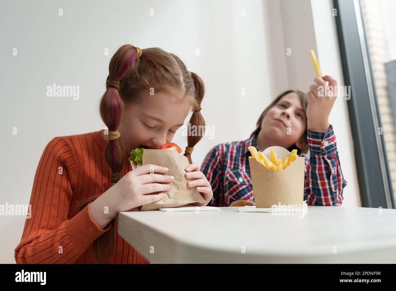 Couple of cute elementary age kids eating fast food for lunch. Two ...