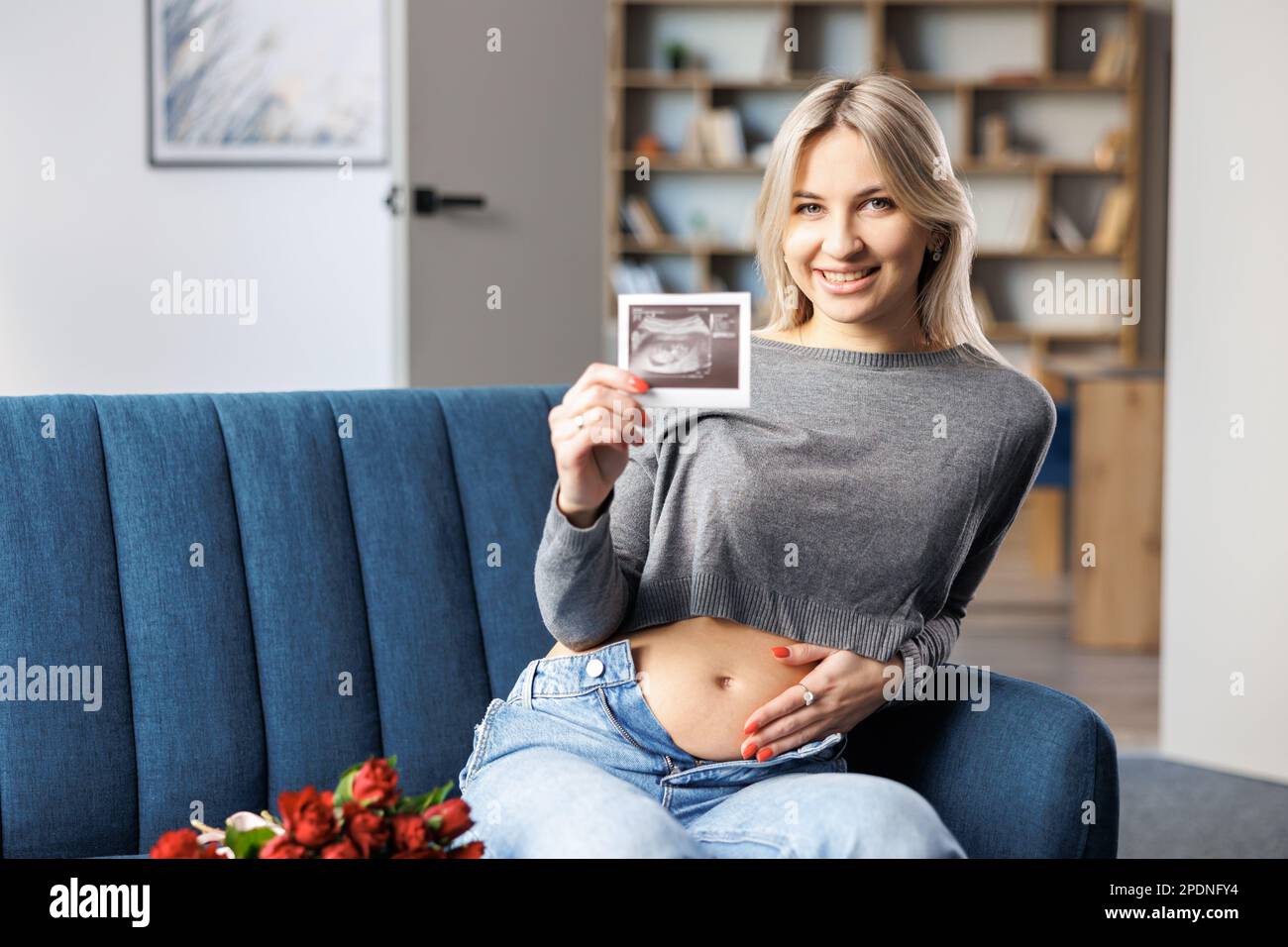 Photo of a pregnant woman at home sitting on couch near beautiful ...
