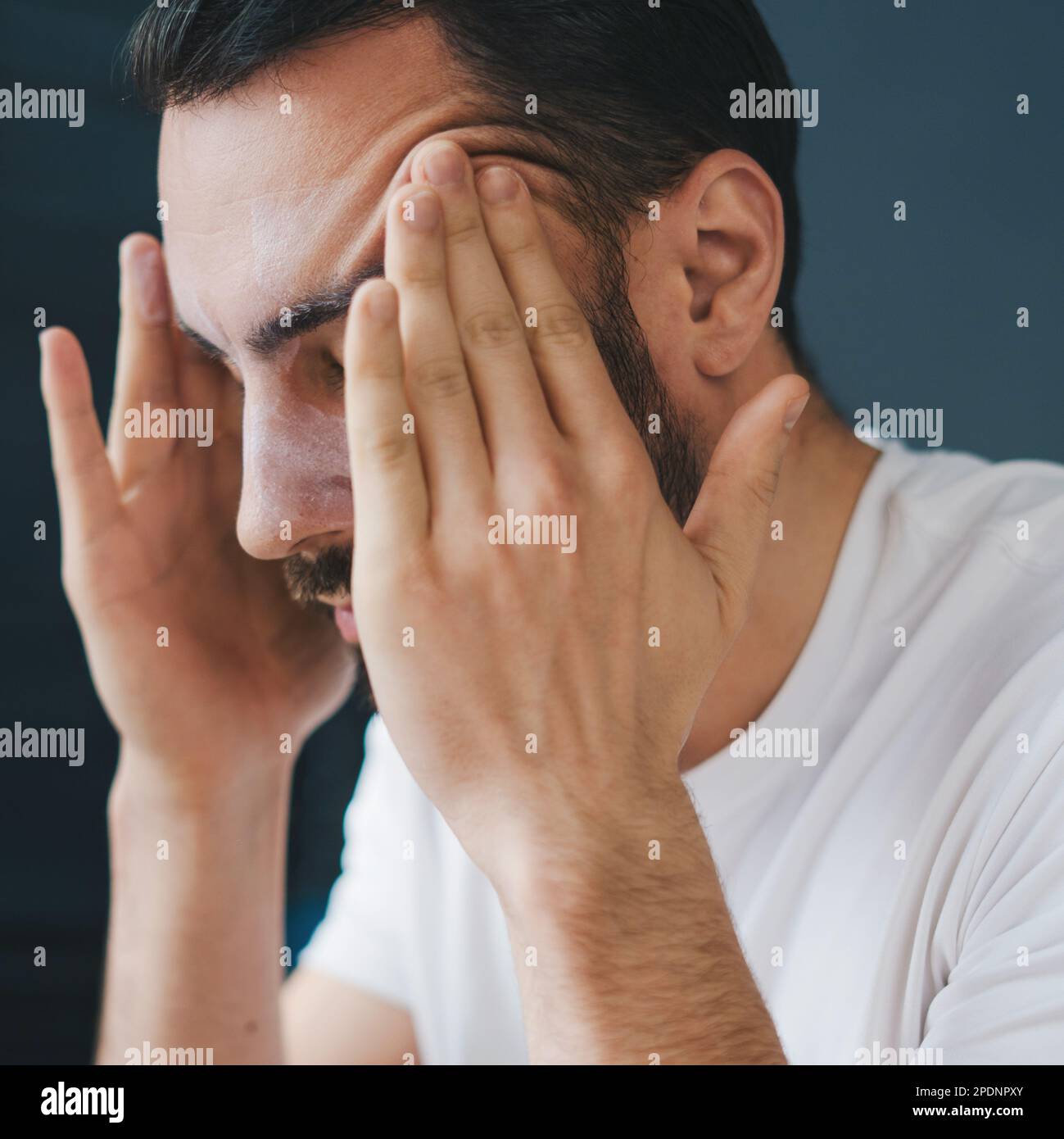 Frustrated young man touching with fingers pressed to forehead, close ...