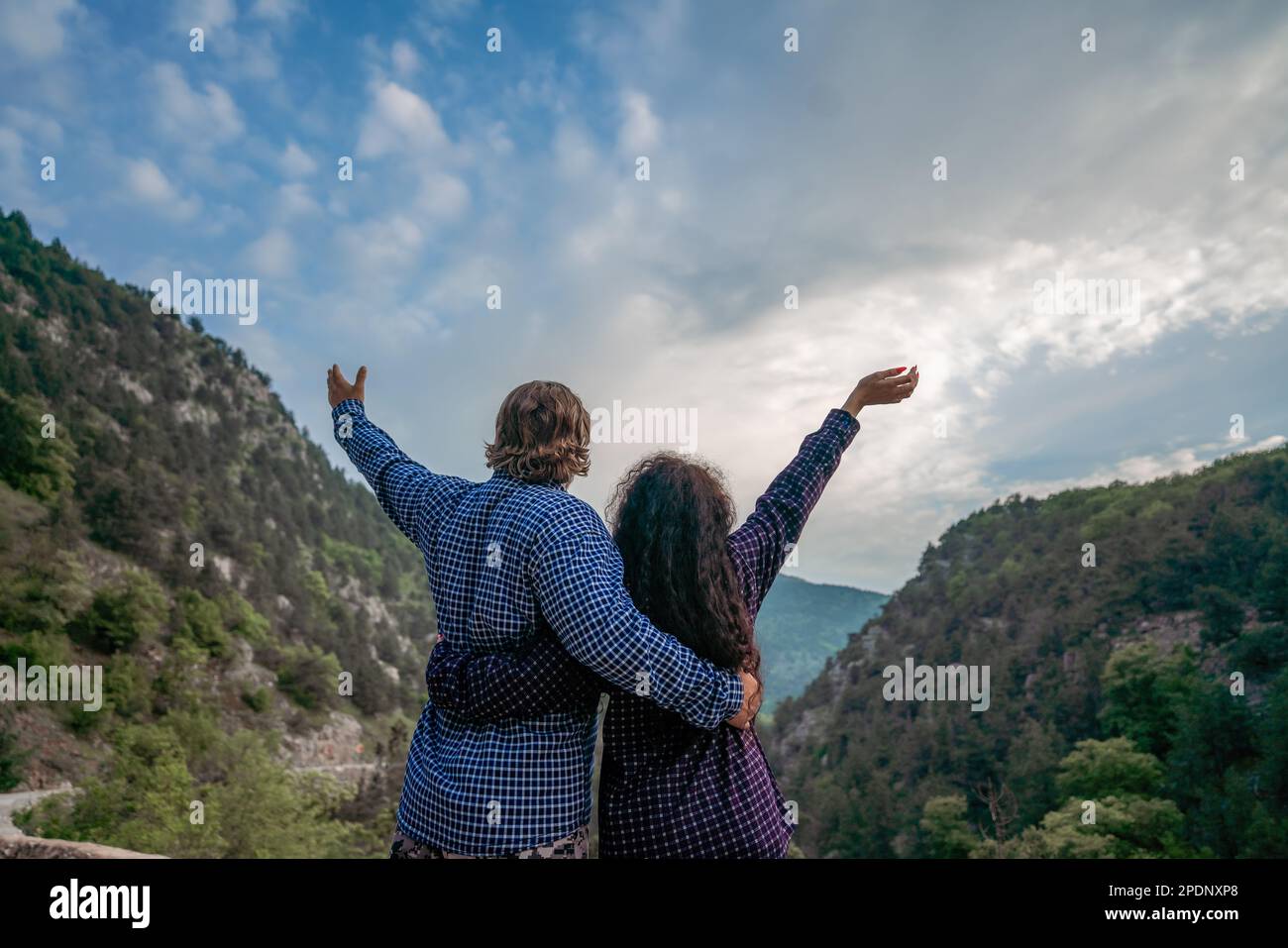 couple in the mountains with their hands up, rejoice in their journey ...