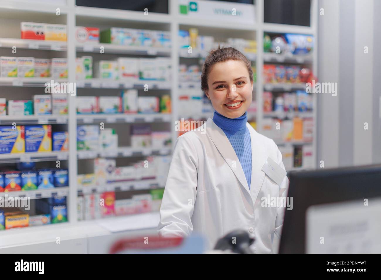 Portrait of young pharmacist selling medication in pharmacy Stock Photo ...