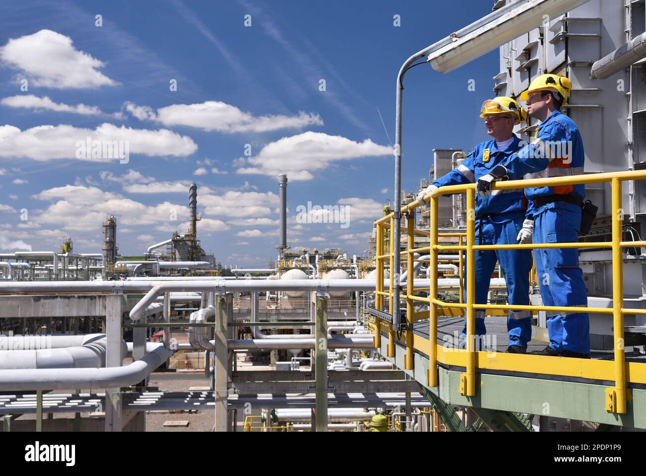 group of industrial workers in a refinery - oil processing equipment ...