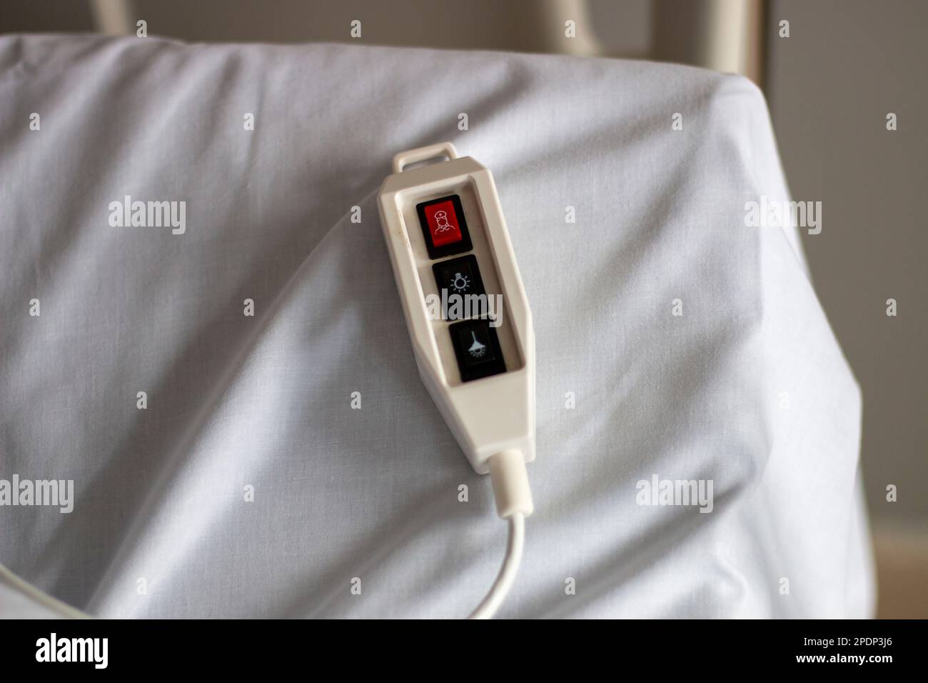 Hospital call control with a red emergency button resting on a bed with ...