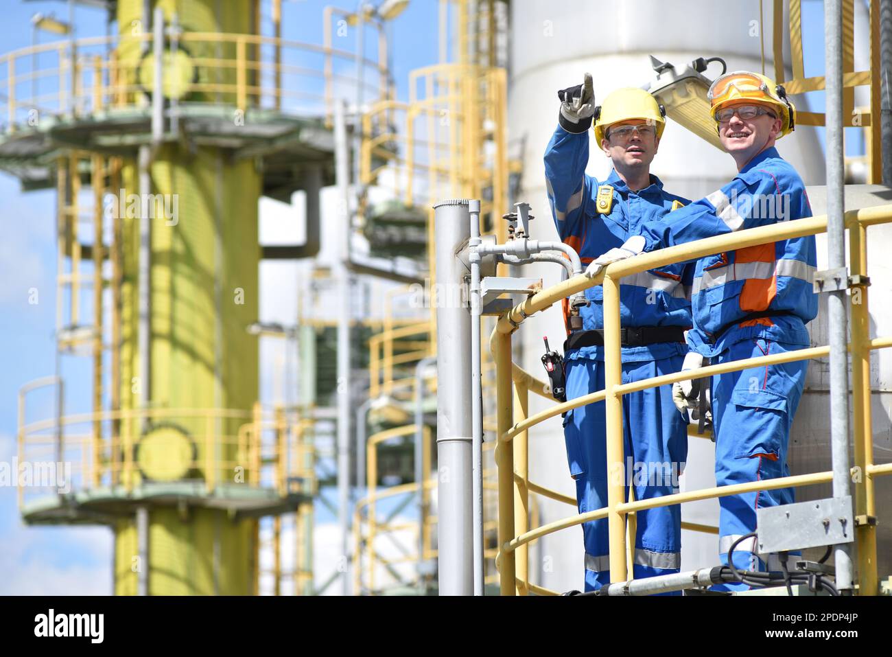 teamwork: group of industrial workers in a refinery - oil processing ...