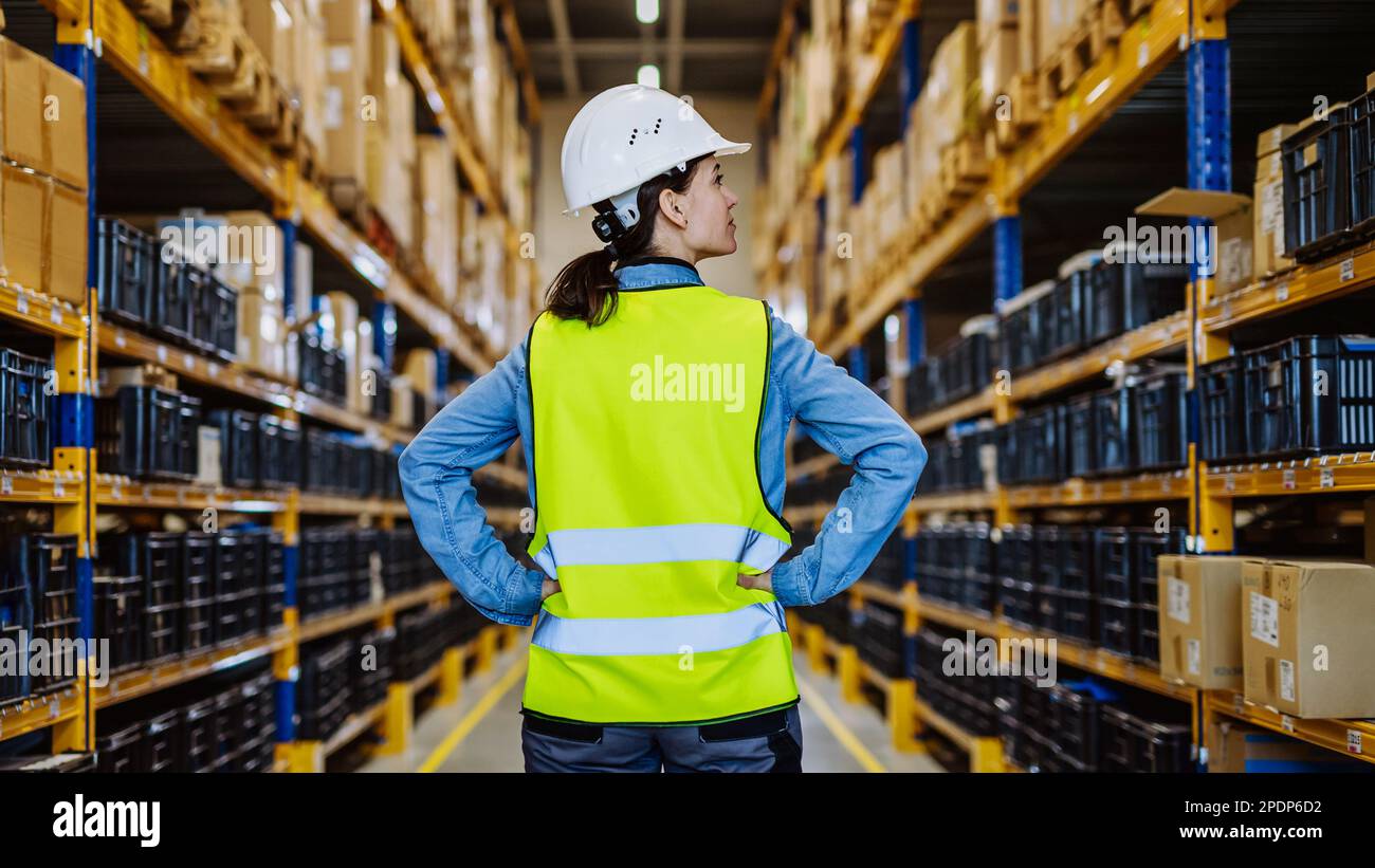 Rear view of warehouse female worker checking up stuff in a warehouse ...