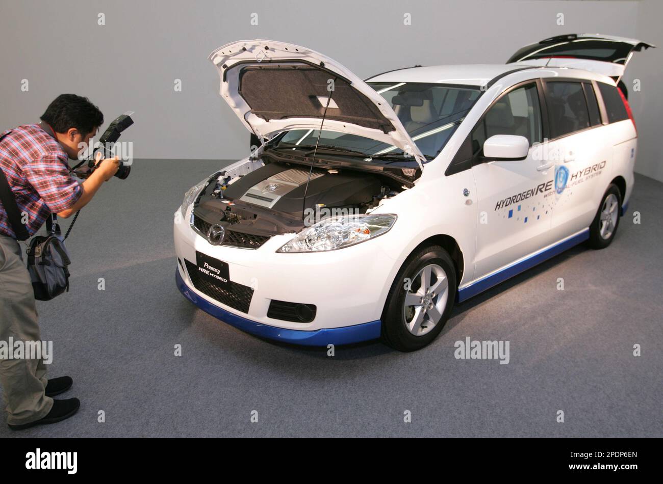 A photographer focuses on an engine of Mazda Motor Corp.'s hybrid ...