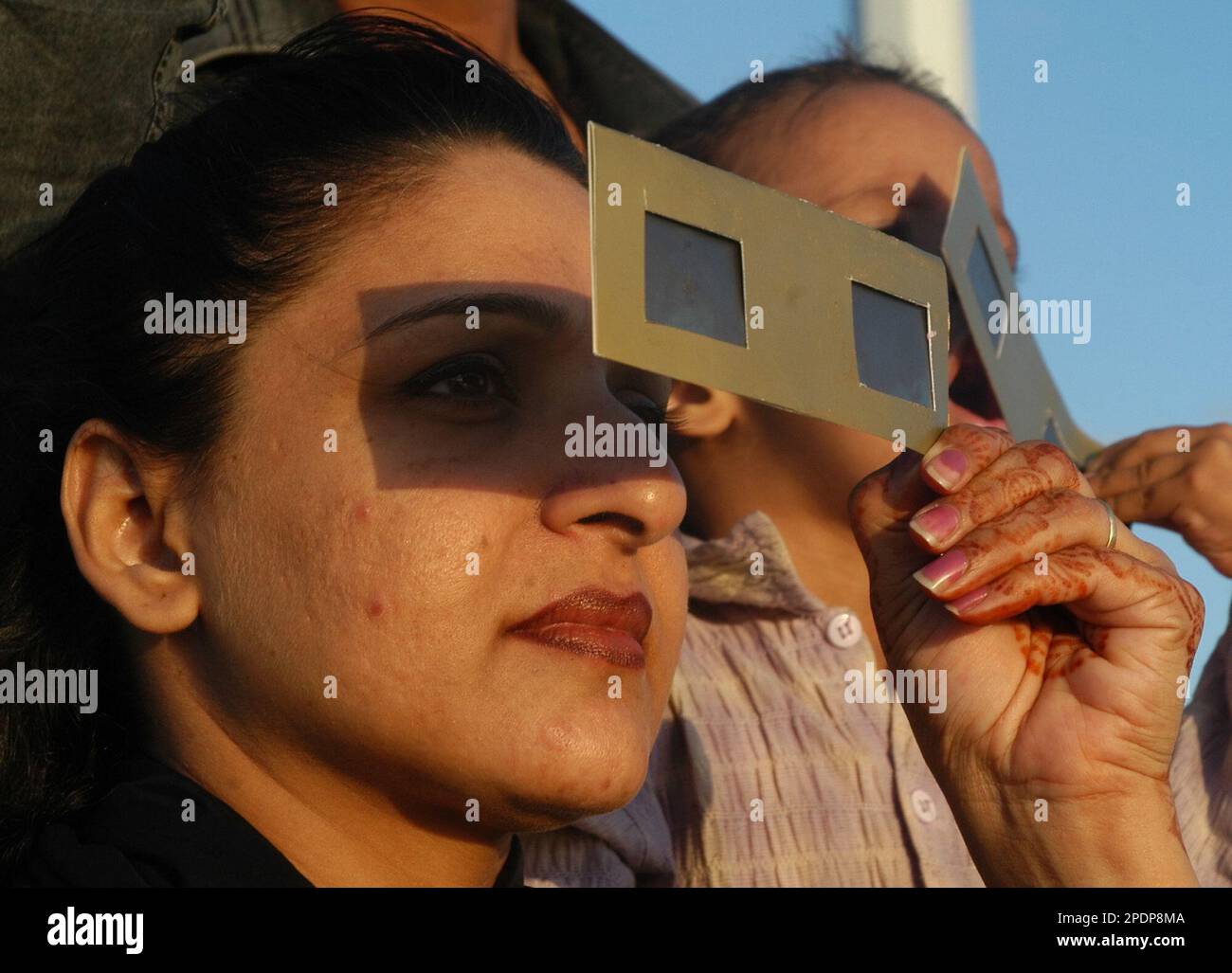 An unidentified Pakistan woman looks at partial solar eclipse with her ...