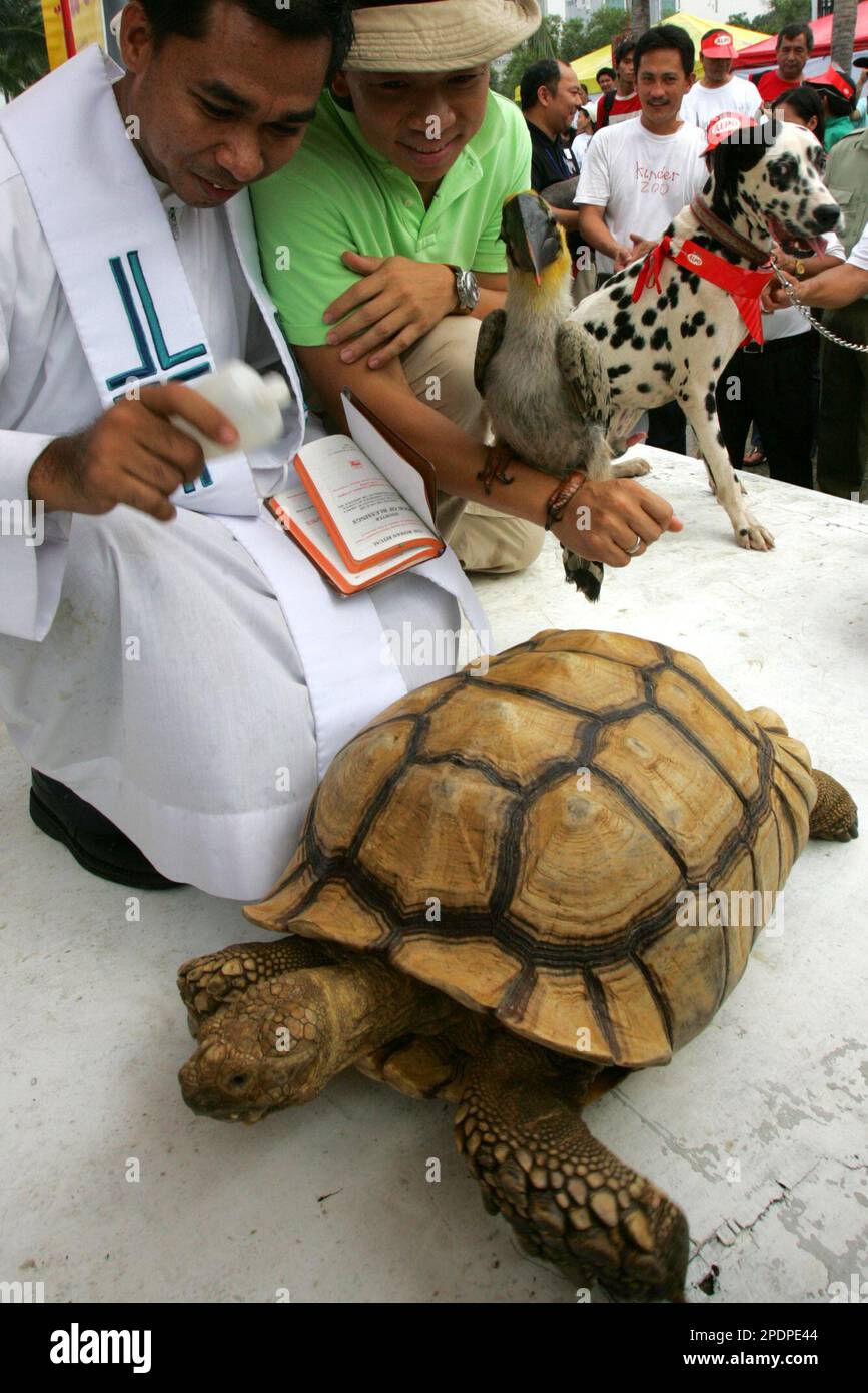 Filipino Catholic priest Father John Barro, left, sprinkles holy water ...