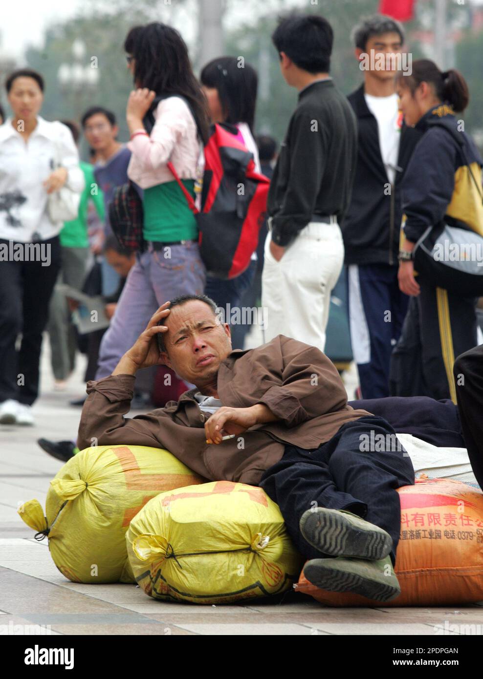 A man rests on his bags at Beijing Railway Station on the eve of China ...