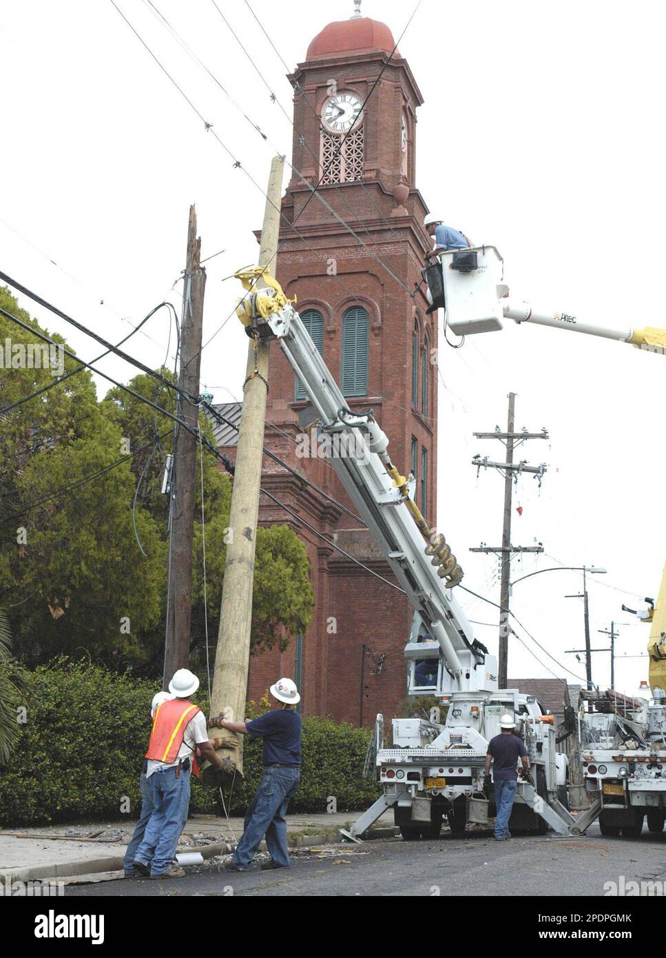 Power crew members from Little Rock, Ark., work to lift a pole in front ...