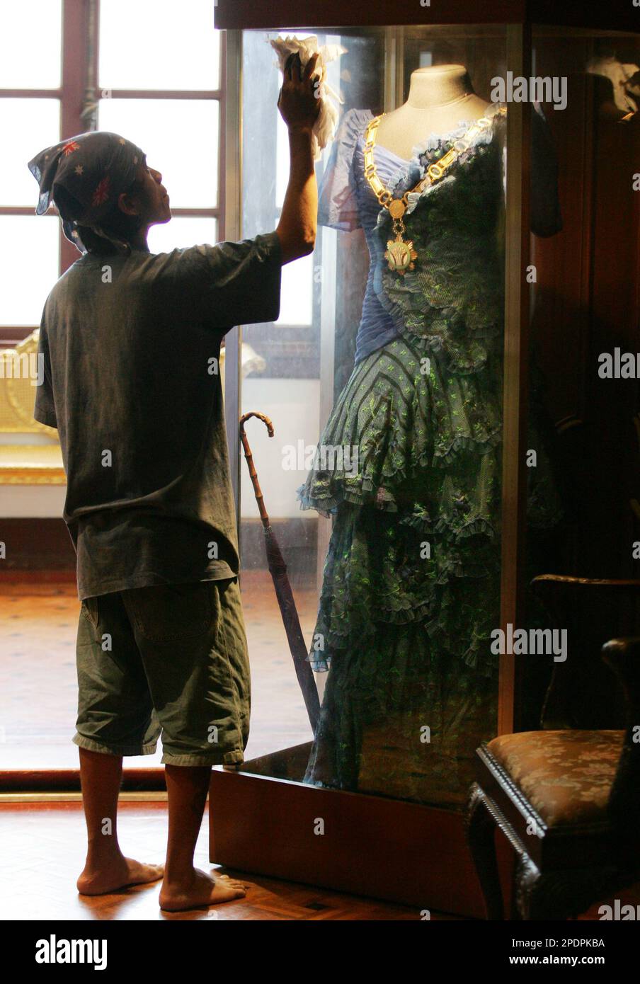 A worker cleans the glass housing a gown of former first lady Imelda ...