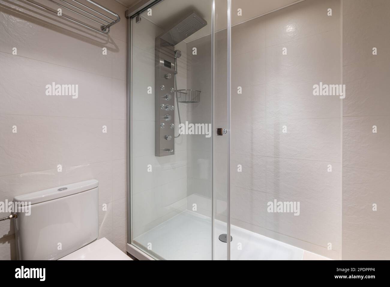 Glassed-in shower with modern controls next to the toilet in a compact ...