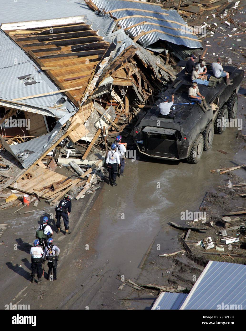 Search and rescue personnel walk through mud in the aftermath of ...