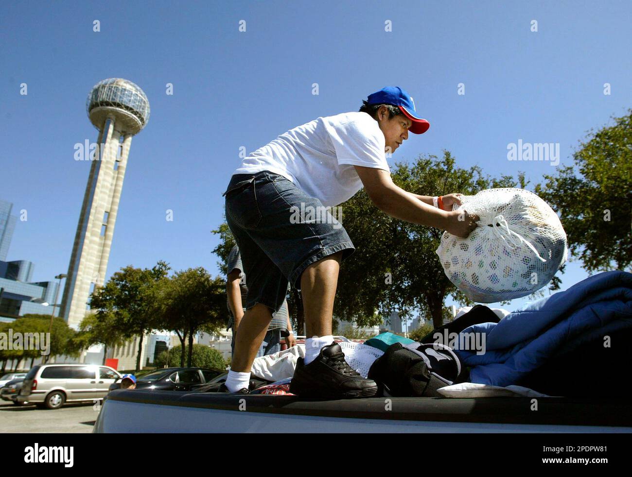 Cesar Avila, 19, a Hurricane Rita evacuee from Galveston, Texas, helps ...