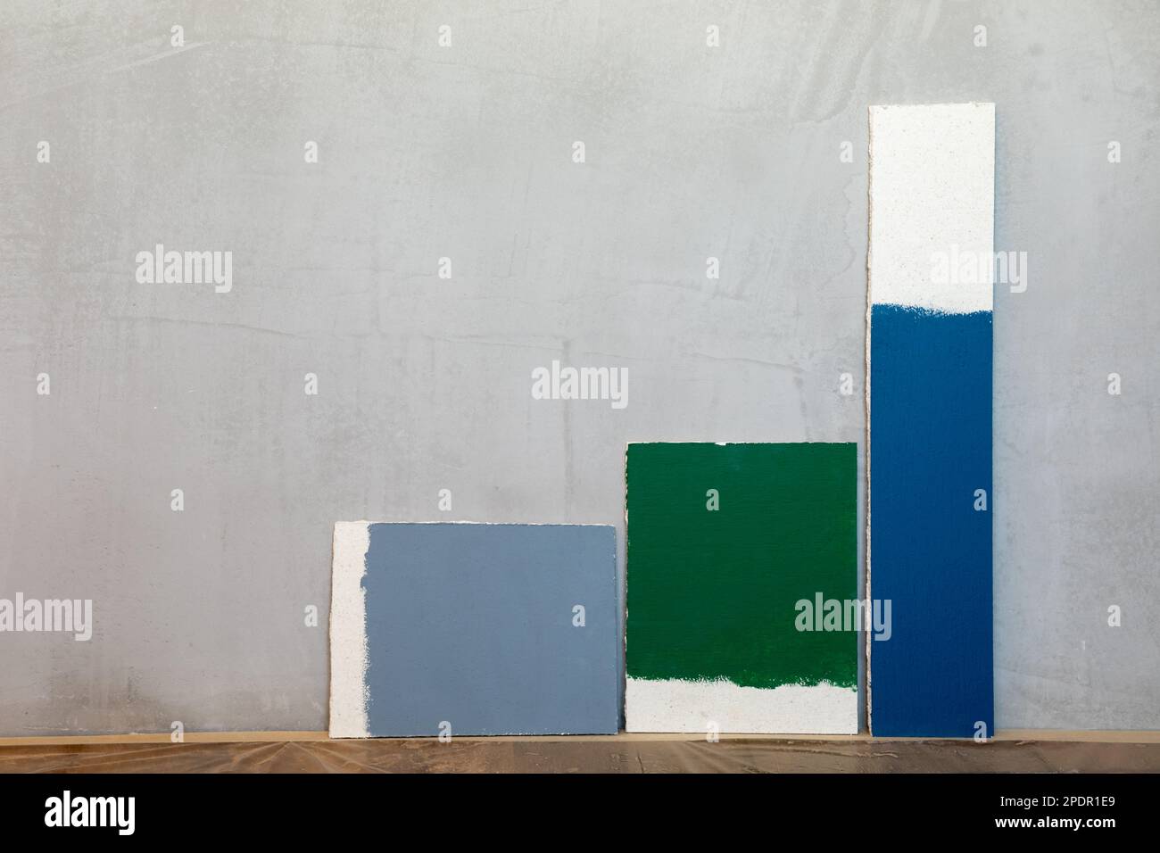 Grey green and blue color samplers at blank gypsum plaster wall ...