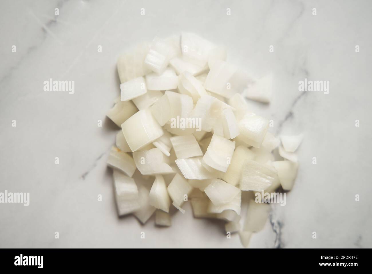 Medium diced onions on white marble background. Photo show how does onion sliced into medium ...