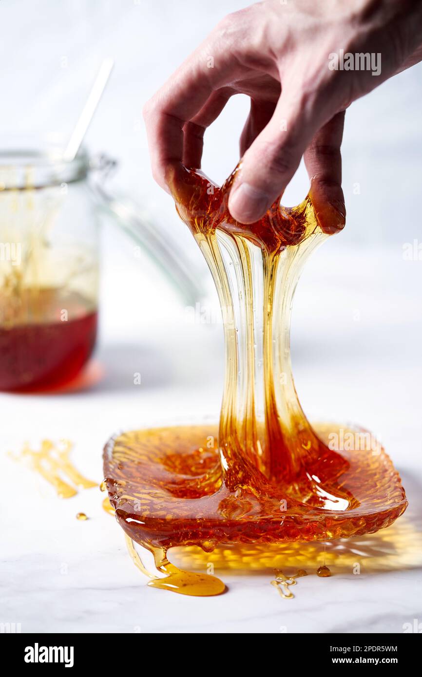 Thick golden syrup or caramel or honey dripping from the spoon into the ...