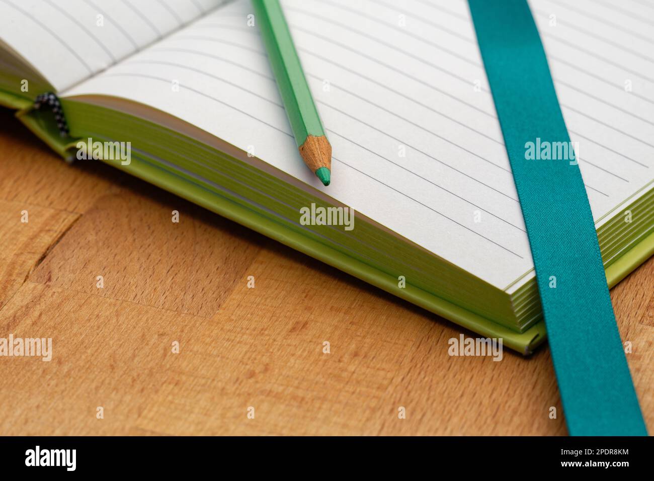 A lined notebook with a green pencil. Ready to take notes, sketch ideas ...