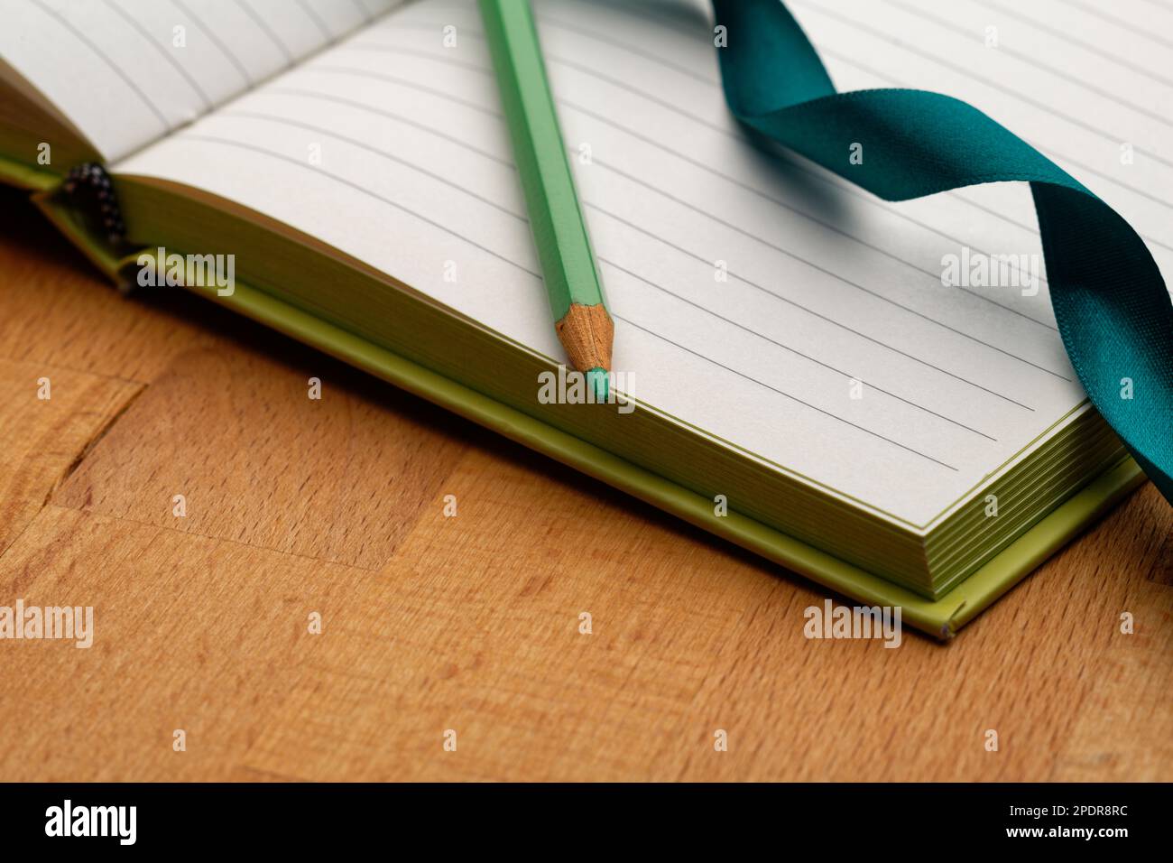 A lined notebook with a green pencil. Ready to take notes, sketch ideas ...
