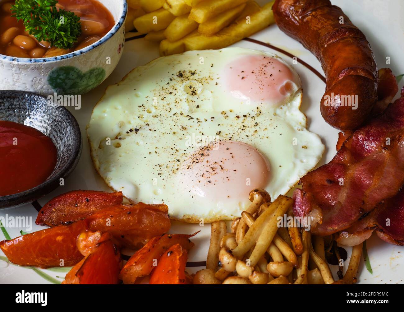 Healthy english breakfast with fried eggs, sausagesm bacon, french fries, bean and tomatoes ...