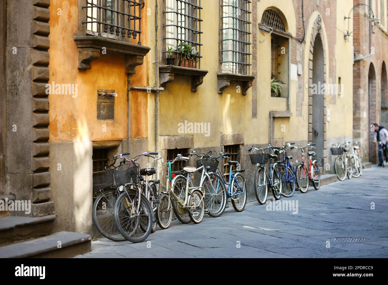 Bicycles parked on beautiful medieval streets of Lucca city, known for ...