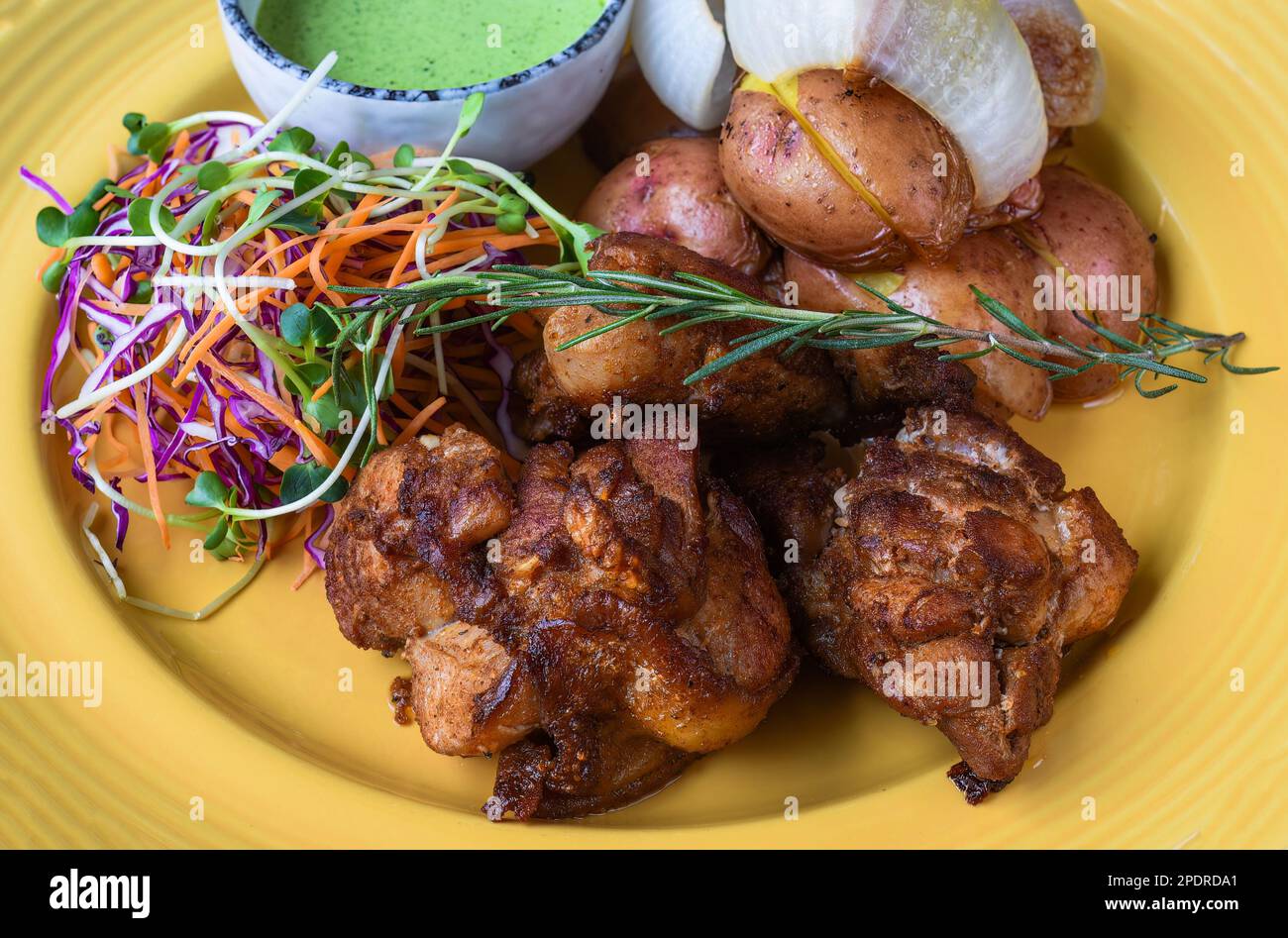 Peruvian Chicken with Green Sauce and salad with potato on yellow plate ...