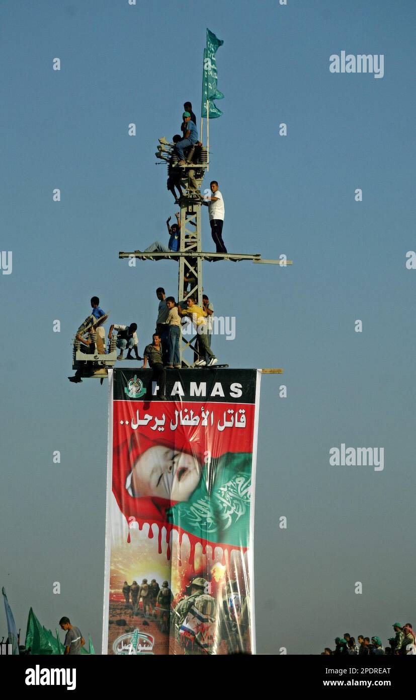 Palestinian watch a Hamas militants from an electric post in the ...
