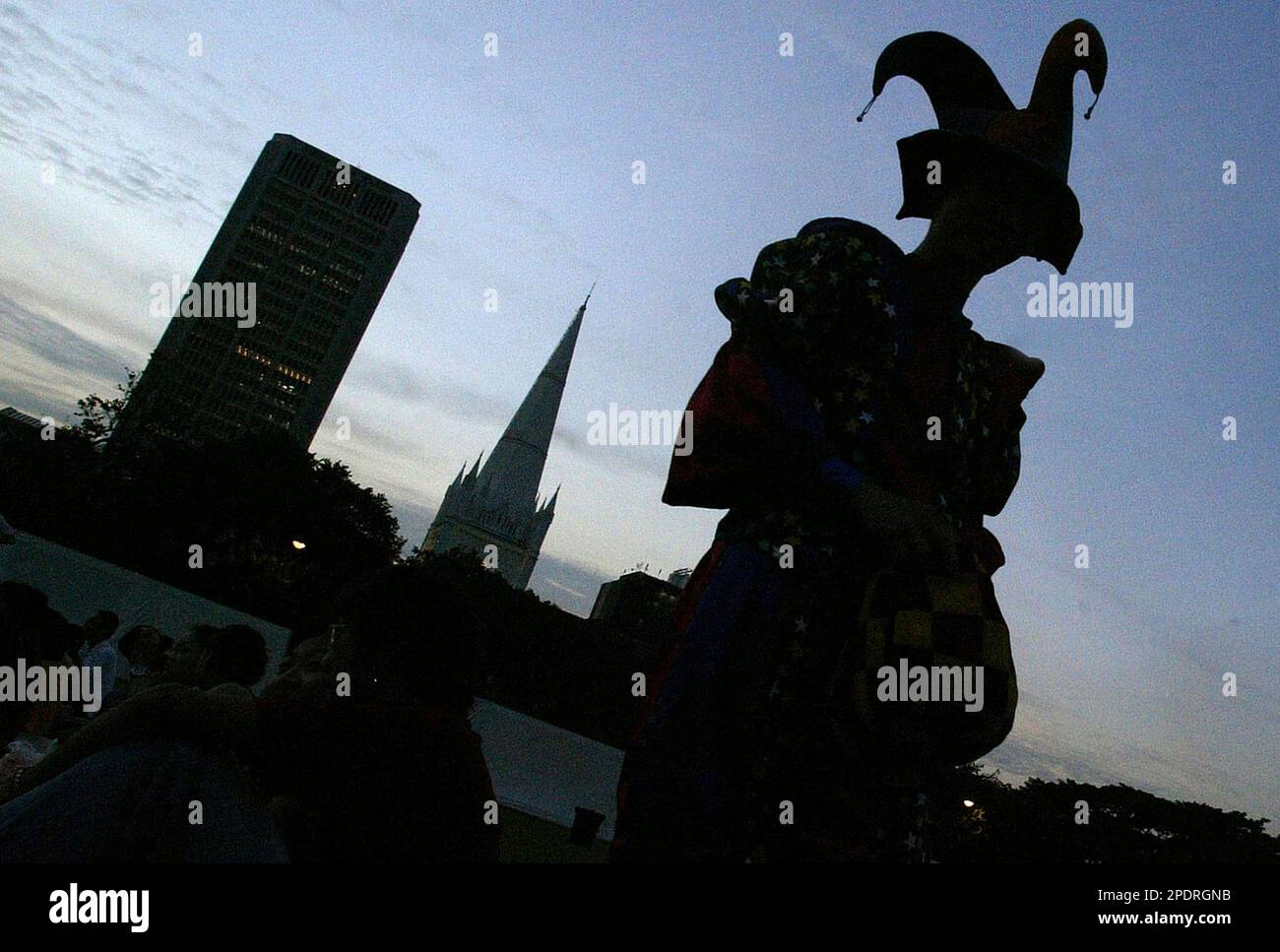 The silhouette of a man dressed as a jester is seen against the evening ...