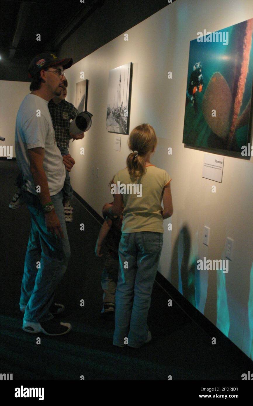 Rex Reynolds and his family walk through photo exhibits of shipwrecks ...