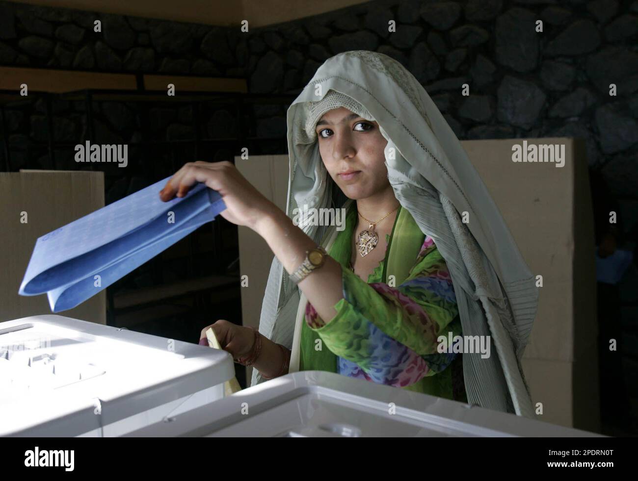 A woman is about to drop her ballot paper in a ballot box in Kandahar ...