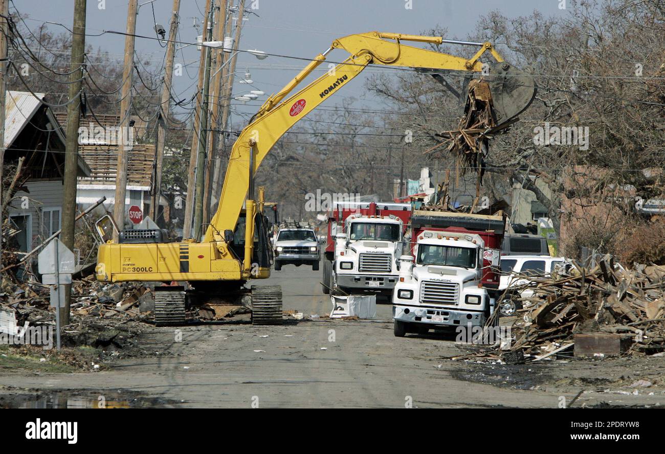 Trucks line up to collect debris from Hurricane Katrina as a payloader ...