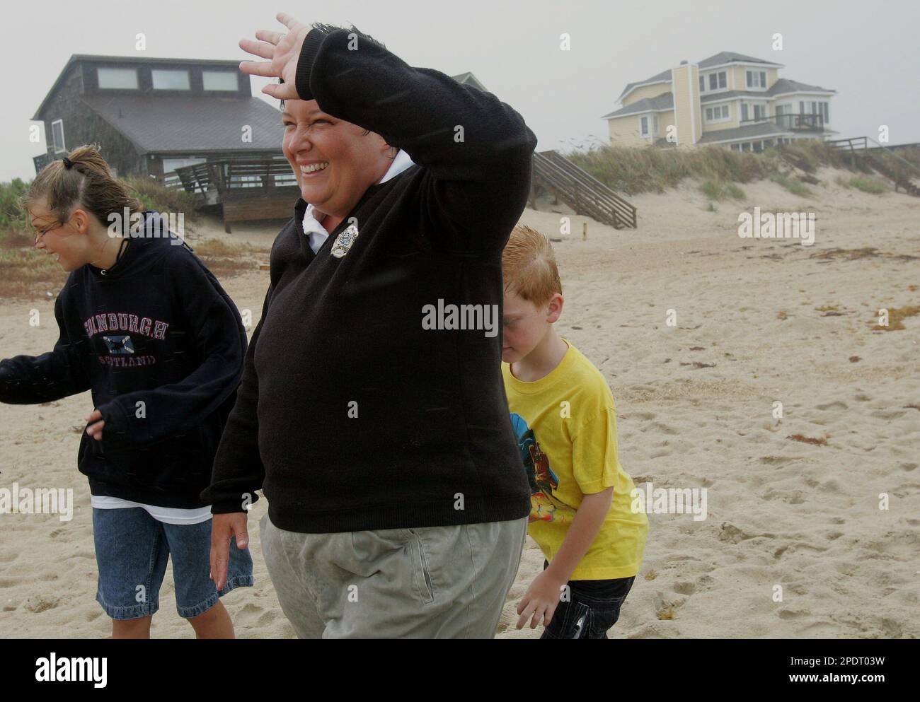 Lisa Merrill shields her face from the blowing water and sand as her ...