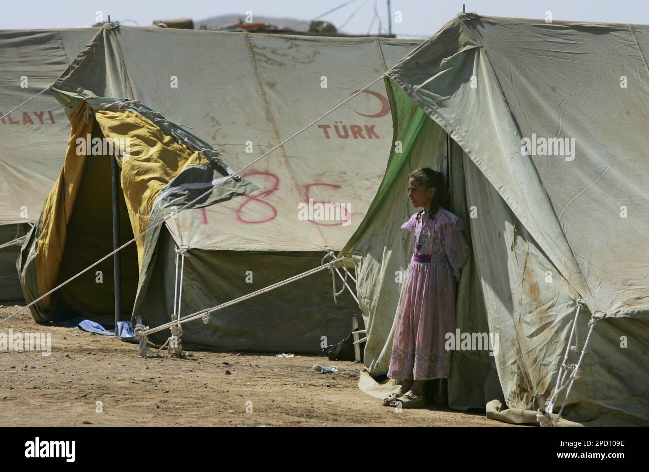 An Iraqi girl stands outside a tent in an Iraqi Red Crescent camp for ...
