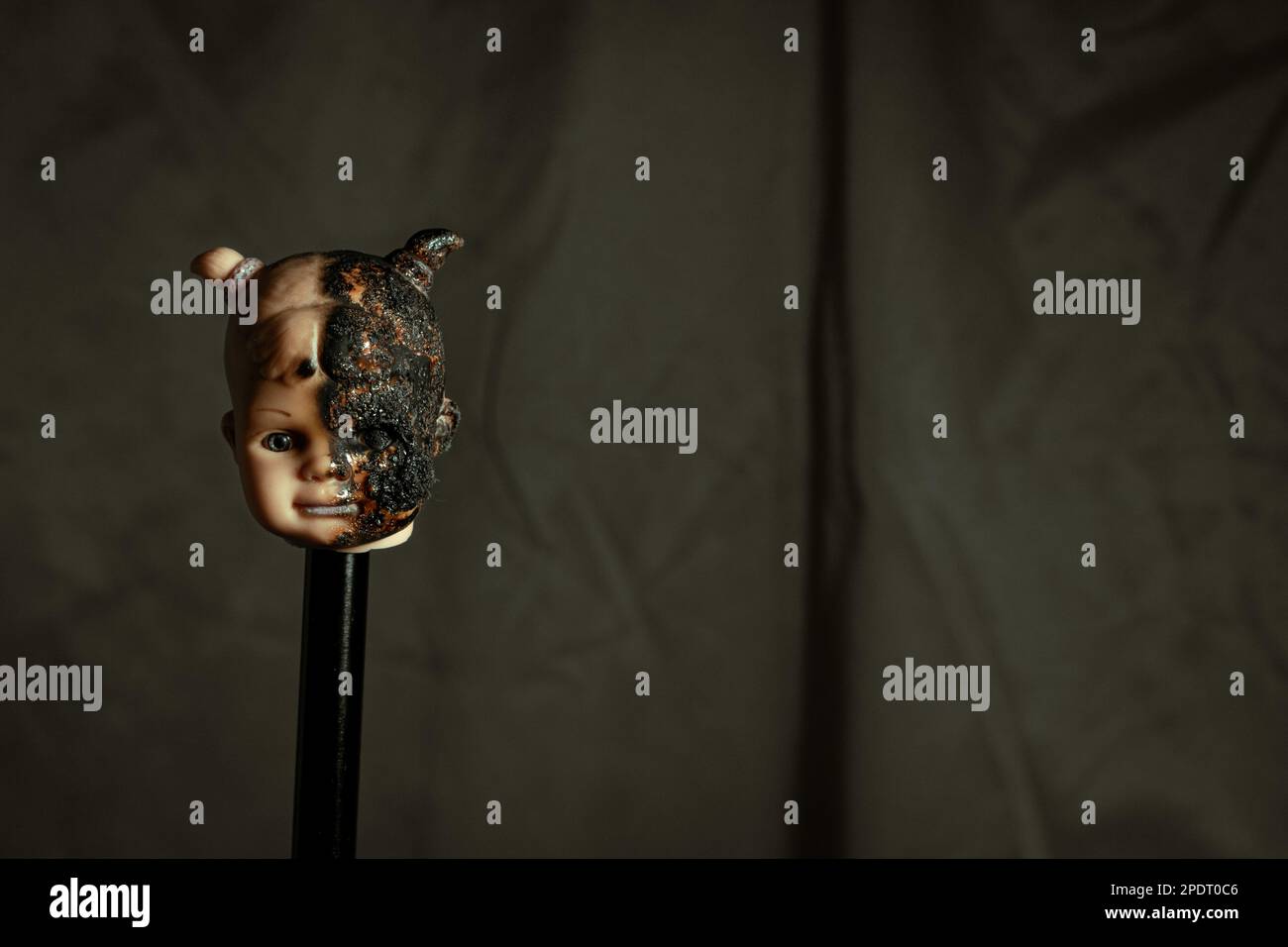 Damaged Dirty burnt Doll head on grey background Stock Photo - Alamy