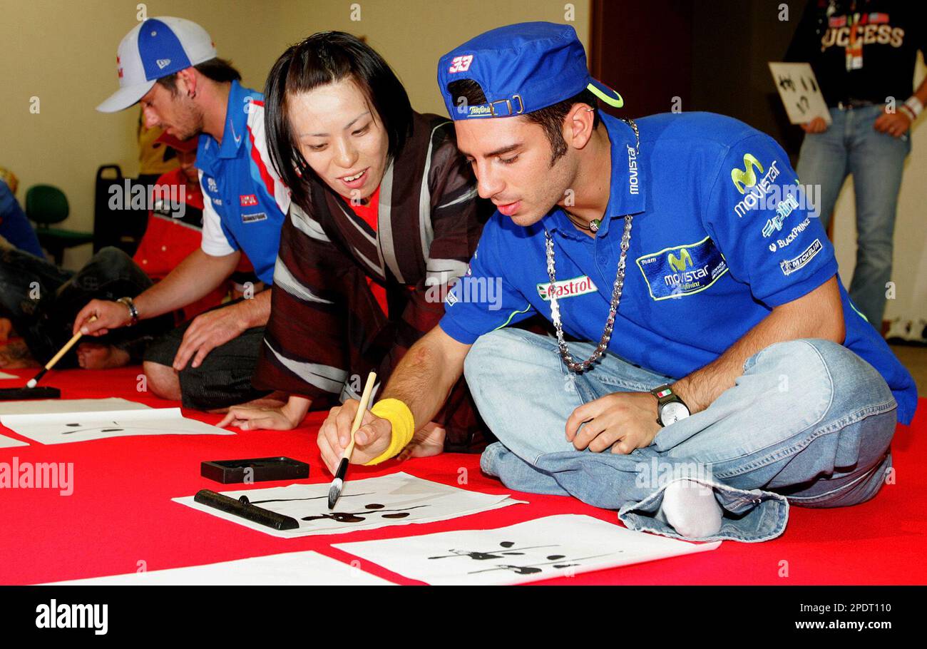 Italian MotoGP rider Marco Melandri, right, uses a brush with help of ...