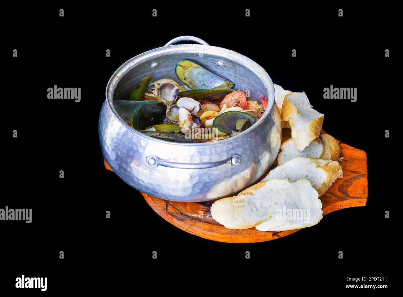 Sautéed seafood in pot close up isolated on black background top view ...