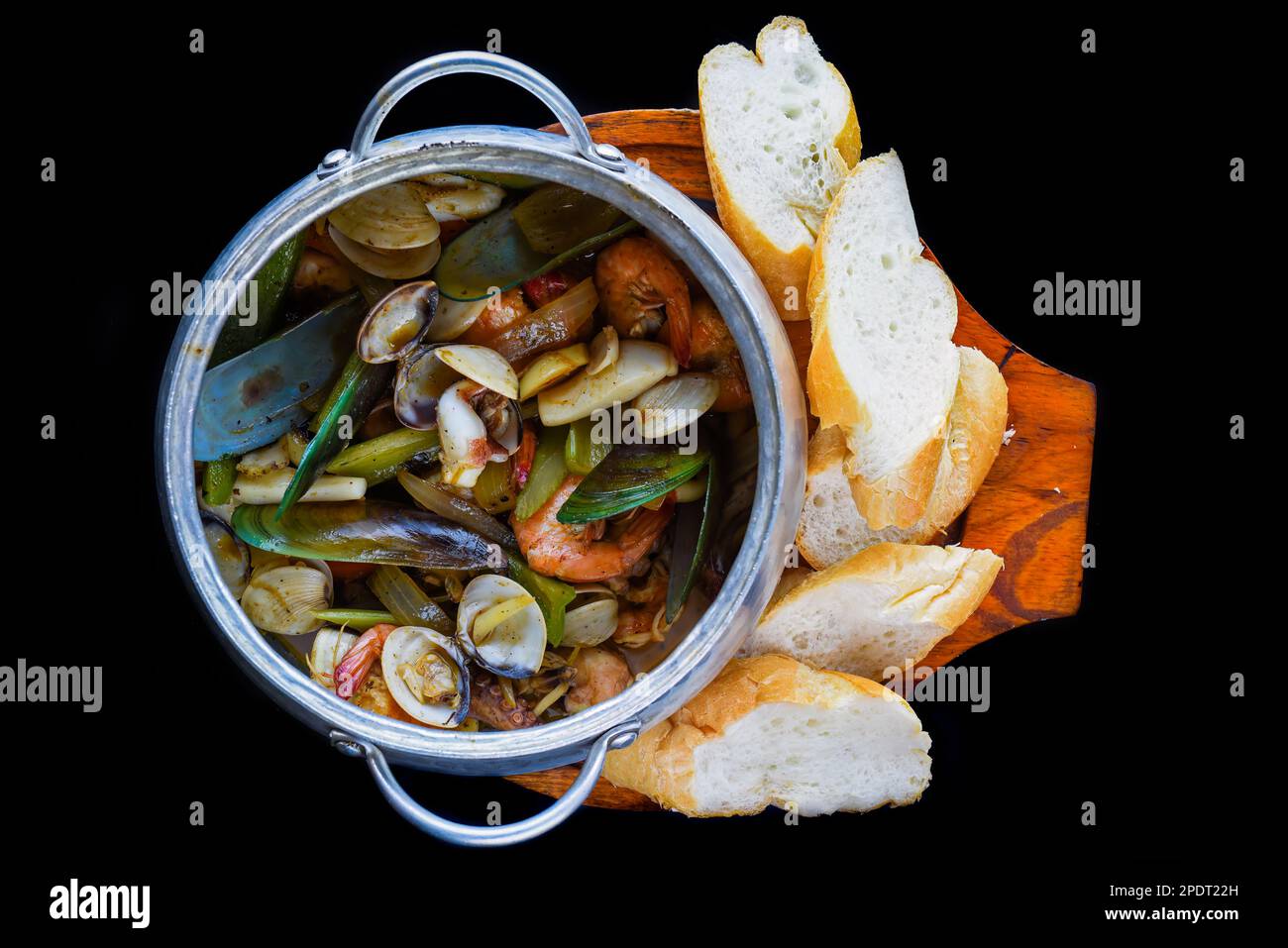 Sautéed seafood in pot close up isolated on black background top view ...