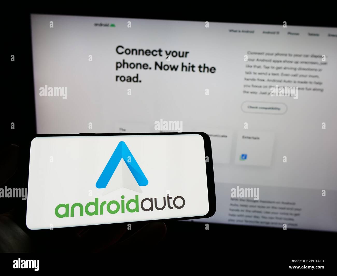 Person holding mobile phone with logo of mobile app Android Auto ...