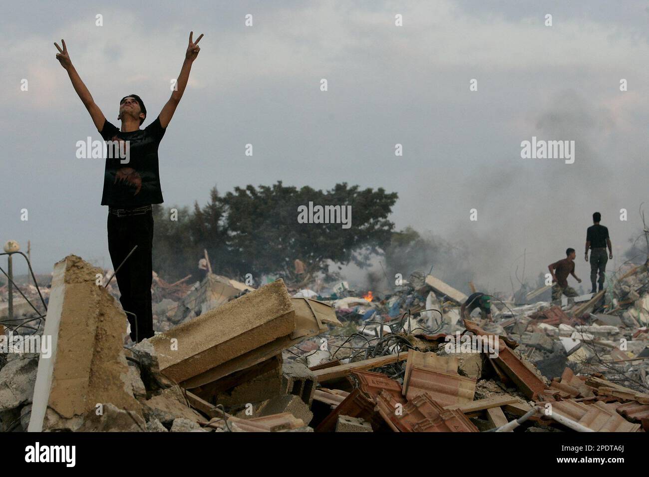 A Palestinian man celebrates in the rubble of demolished houses in the ...