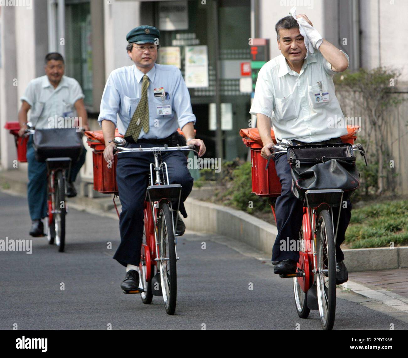 Three postmen ride the red postal bikes in Tokyo Thursday, Aug. 11 ...