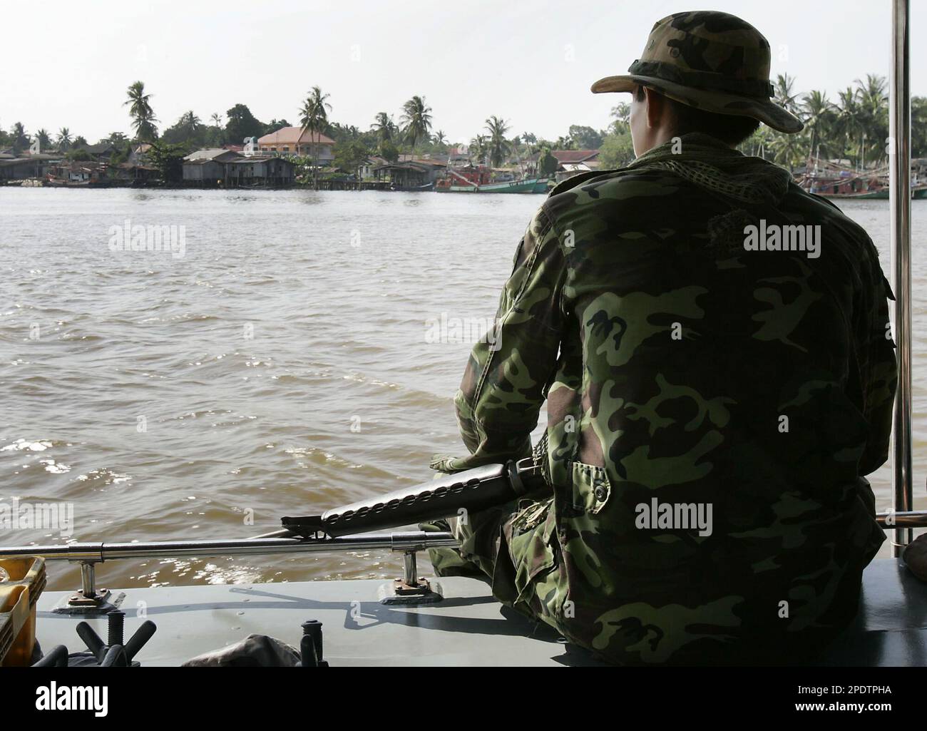 A Thai marine police officer looks from his boat to the Thai side while ...