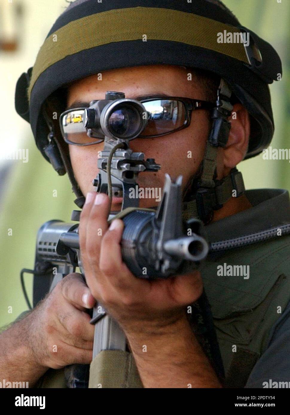 An Israeli border police officer points his weapon as he guards a group ...